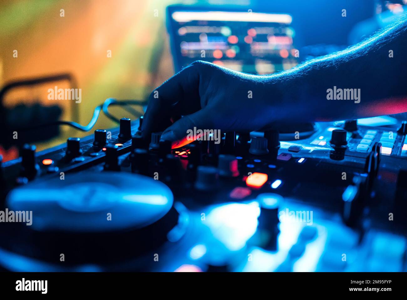 hand of the DJ moves the volume control and mixing music on a mixer at ...