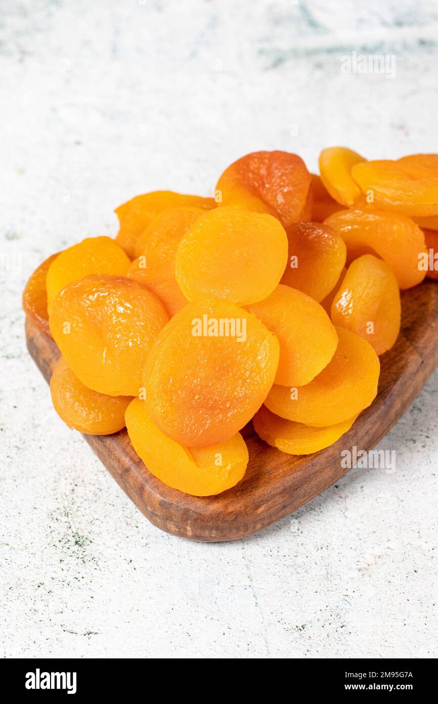 Dried apricots on wooden serving board on stone background. Sun-dried ...