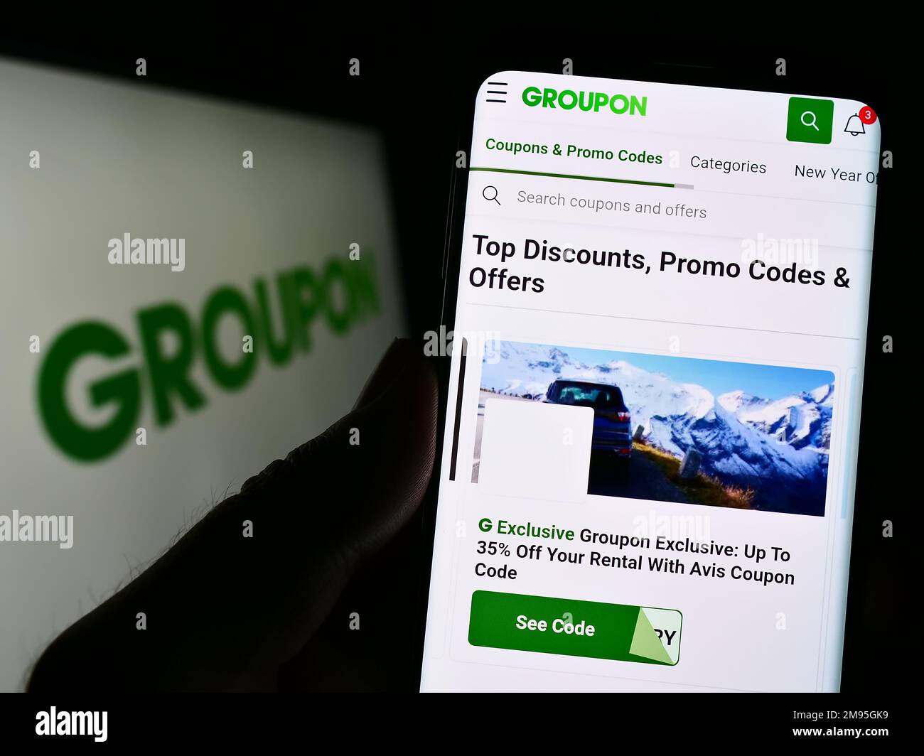 Person holding smartphone with webpage of US e-commerce company Groupon ...