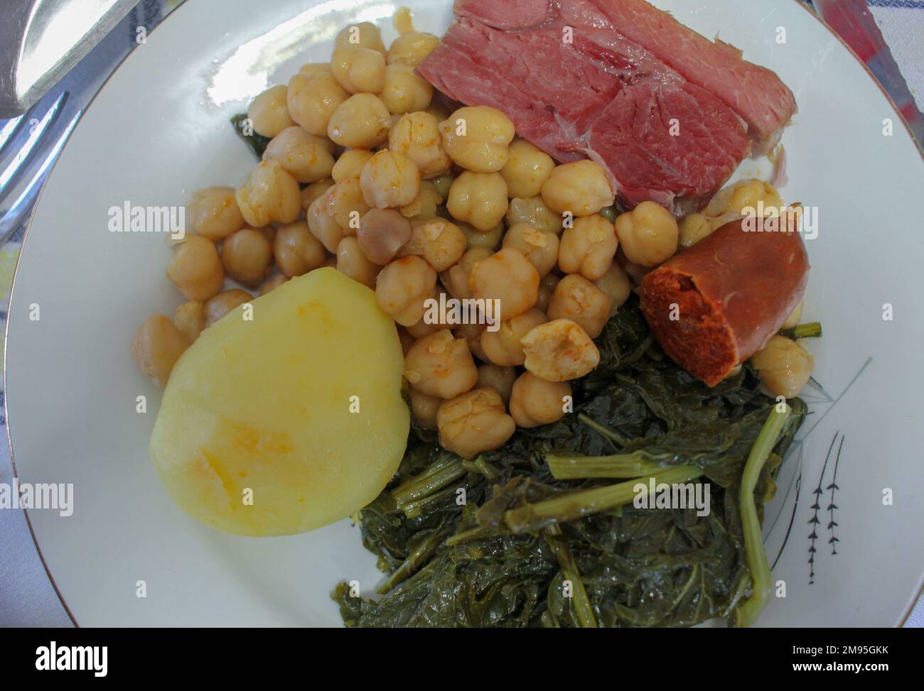 a typical spanish dish, cooked pork legs with potatoes, chickpeas and ...