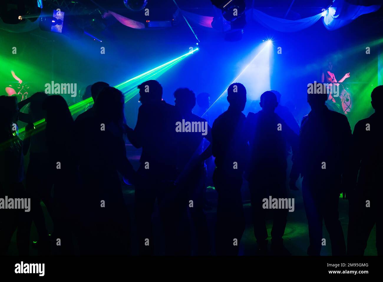 people silhouettes on the dance floor of a night club to laser ...