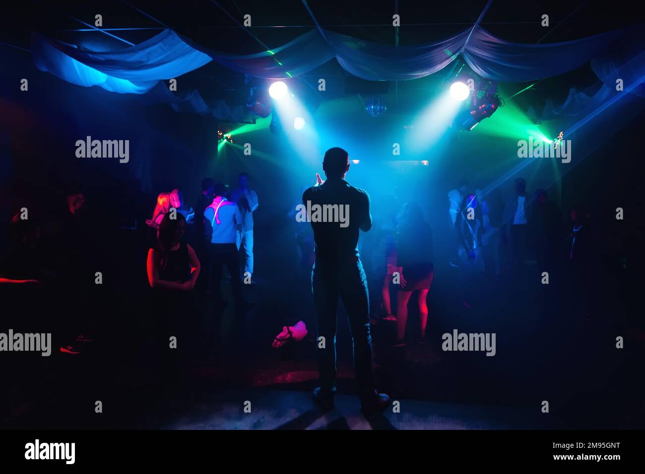 silhouette of the presenter on stage at a concert in a nightclub with a ...