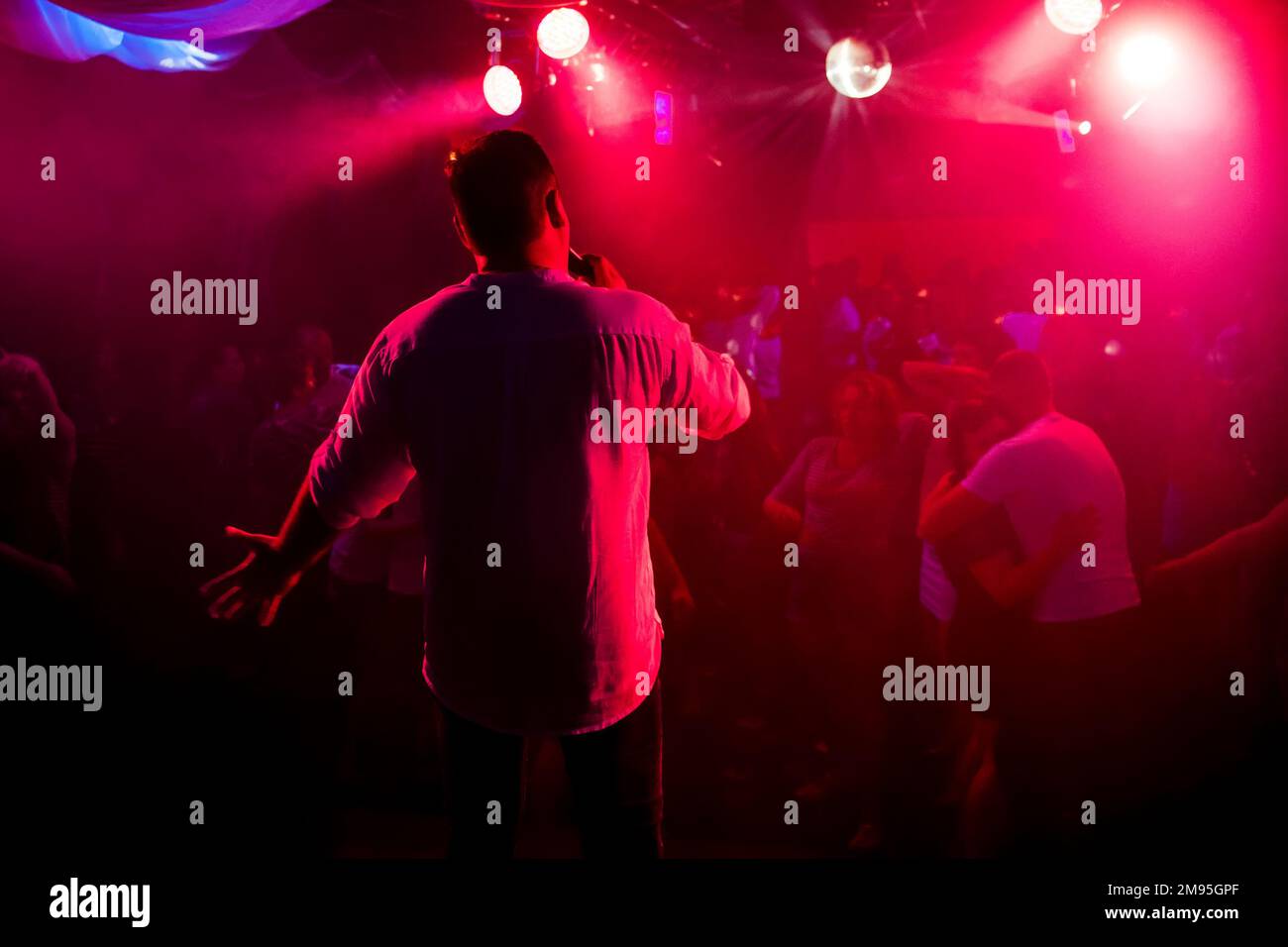 silhouette of the presenter with the microphone in hand on stage at a ...