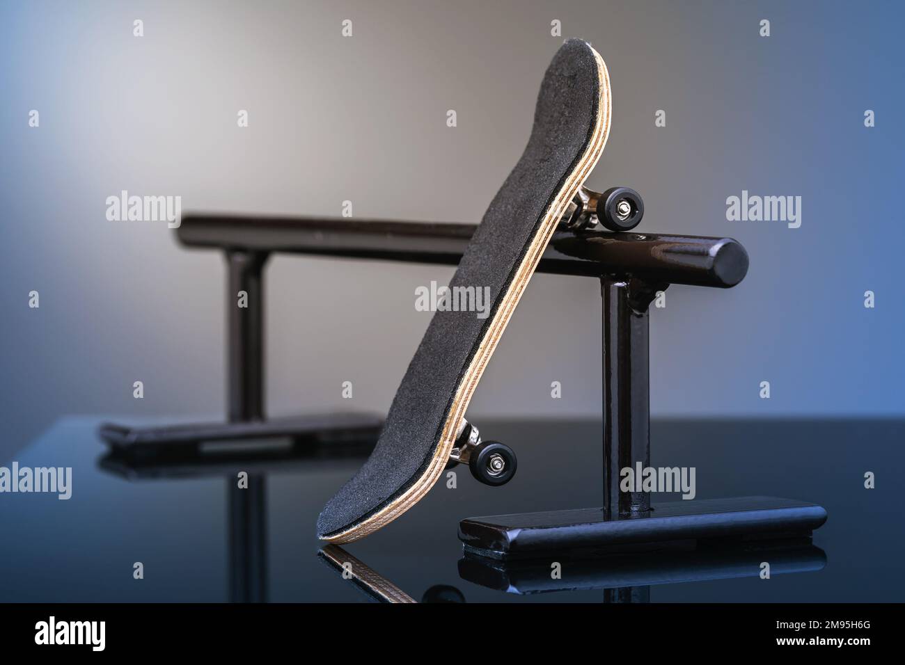 A small fingerboard and metal railing in black on a gradient colored ...