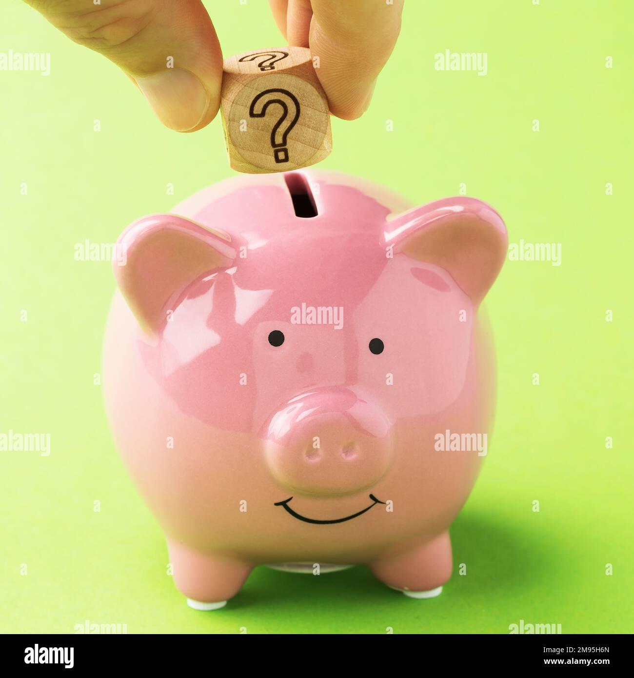 A hand holds a wooden cube with a question mark on the background of a ...