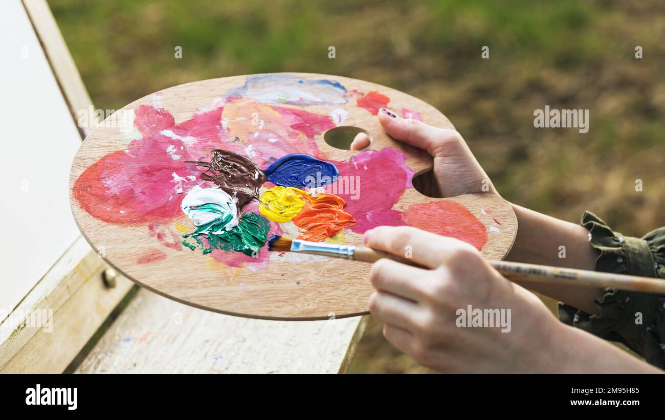 Palette with paints in the hands of an artist painting on the street ...