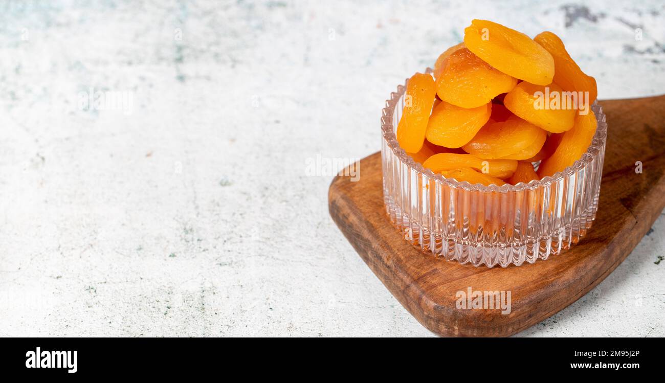 Dried apricots in glass bowl on stone background. Sun-dried yellow ...
