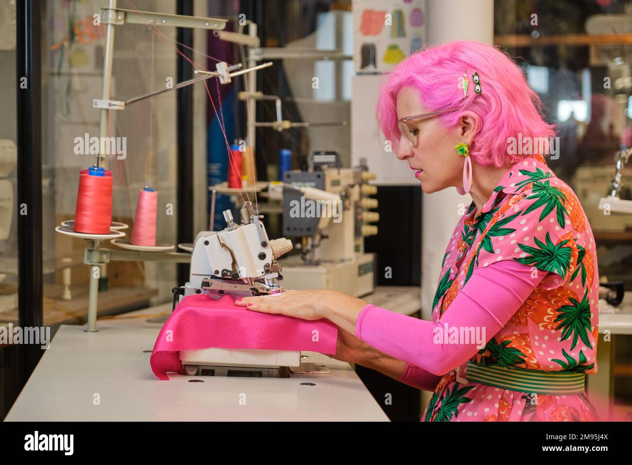 Dressmaker with pink hair and colorfull clothes working on an ...