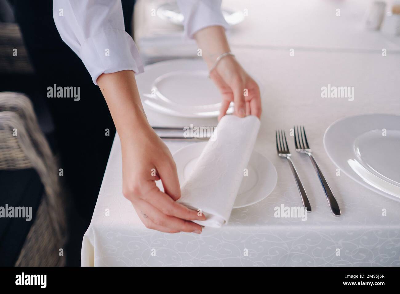 The waiter puts a white napkin on the plate. Beautiful table setting ...