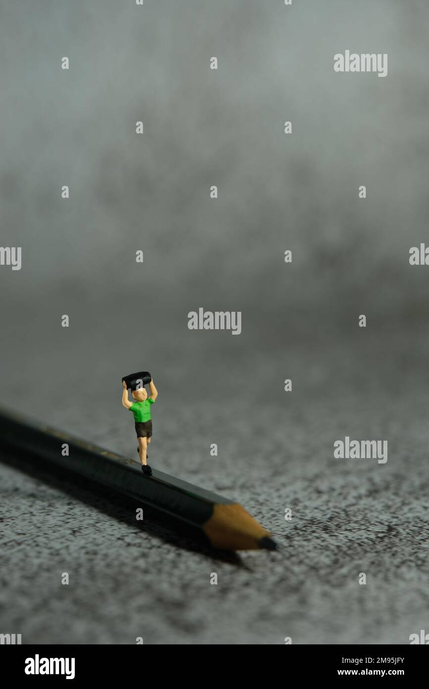 Miniature people toy figure photography. A boy running above pencil ...