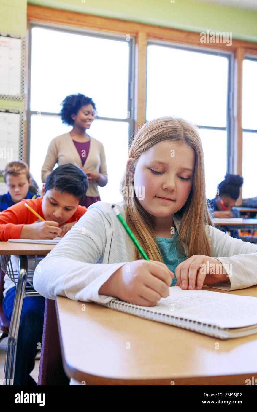 School, girl and writing in book, education and studying for test, exam ...