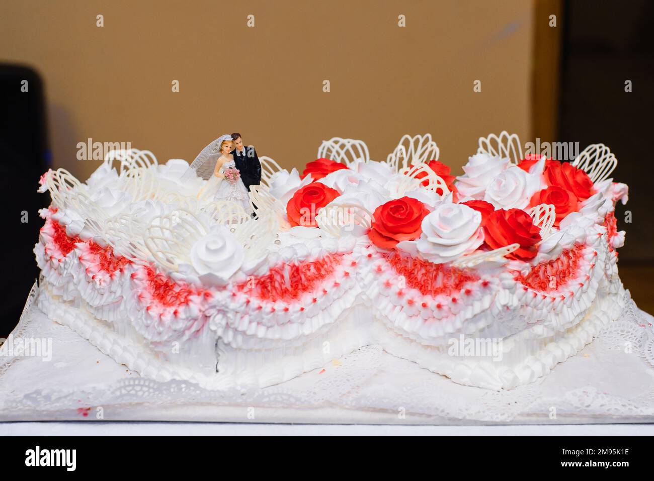 white wedding cake with red flowers cream and puppets of the bride and ...