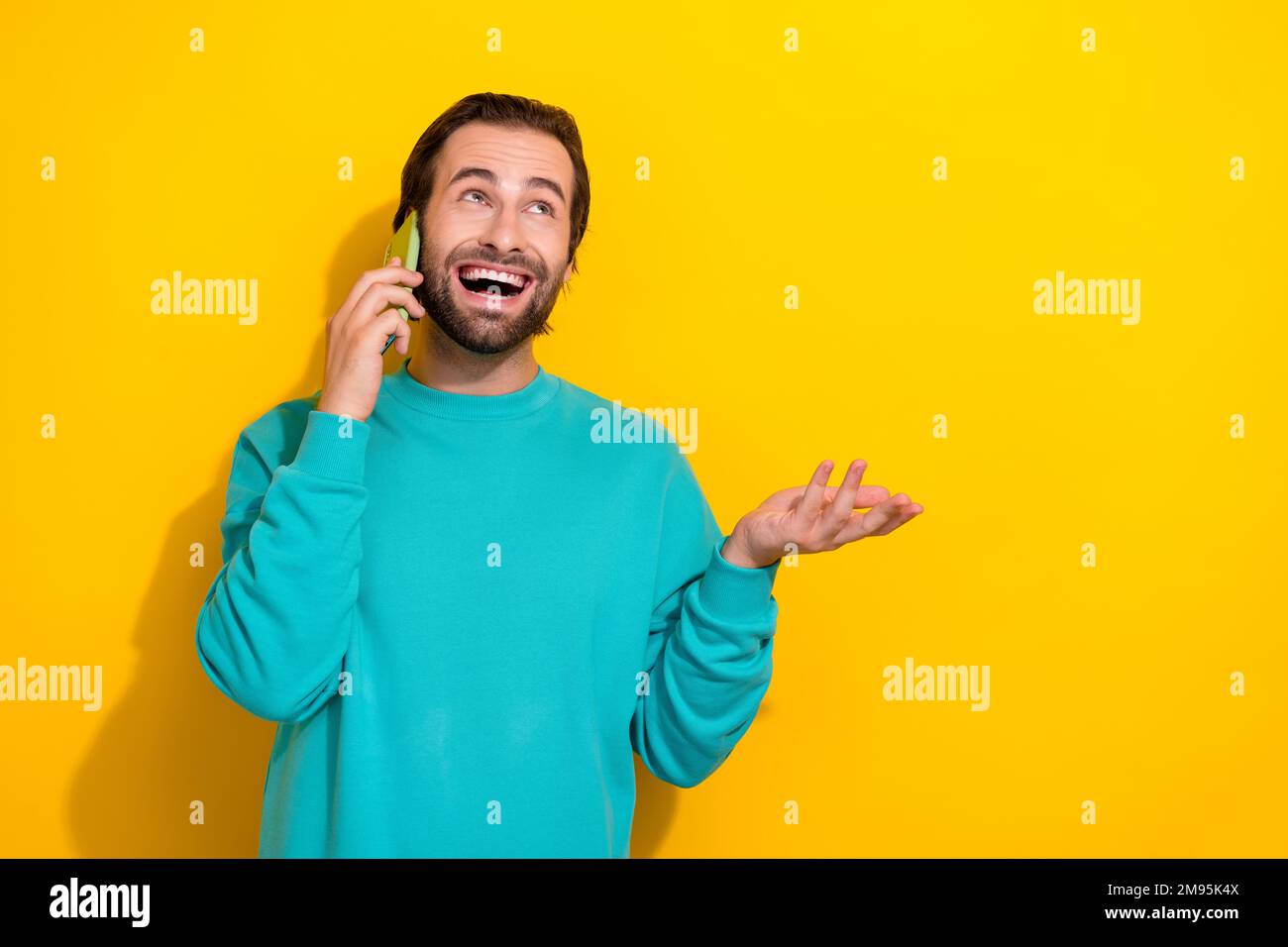 Photo of dreamy funny man wear turquoise clothes talking modern device ...