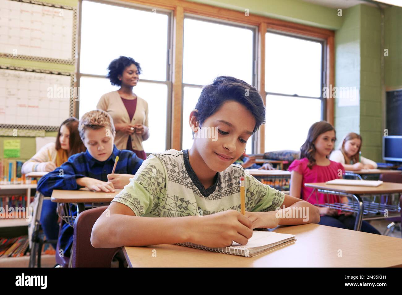 Child, education or student in classroom writing in notebook for ...