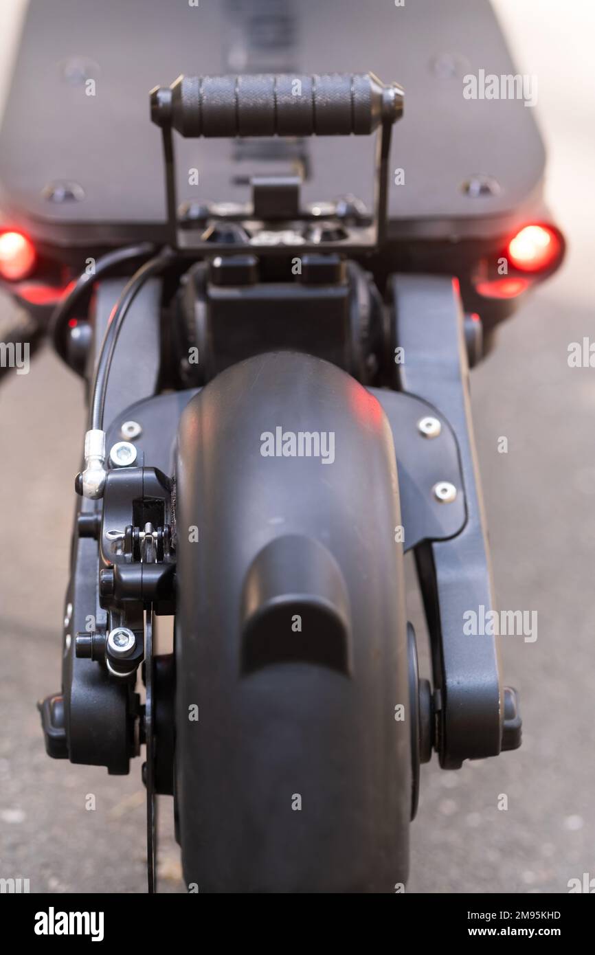 The back of the electric scooter with a foot rest on the asphalt ...