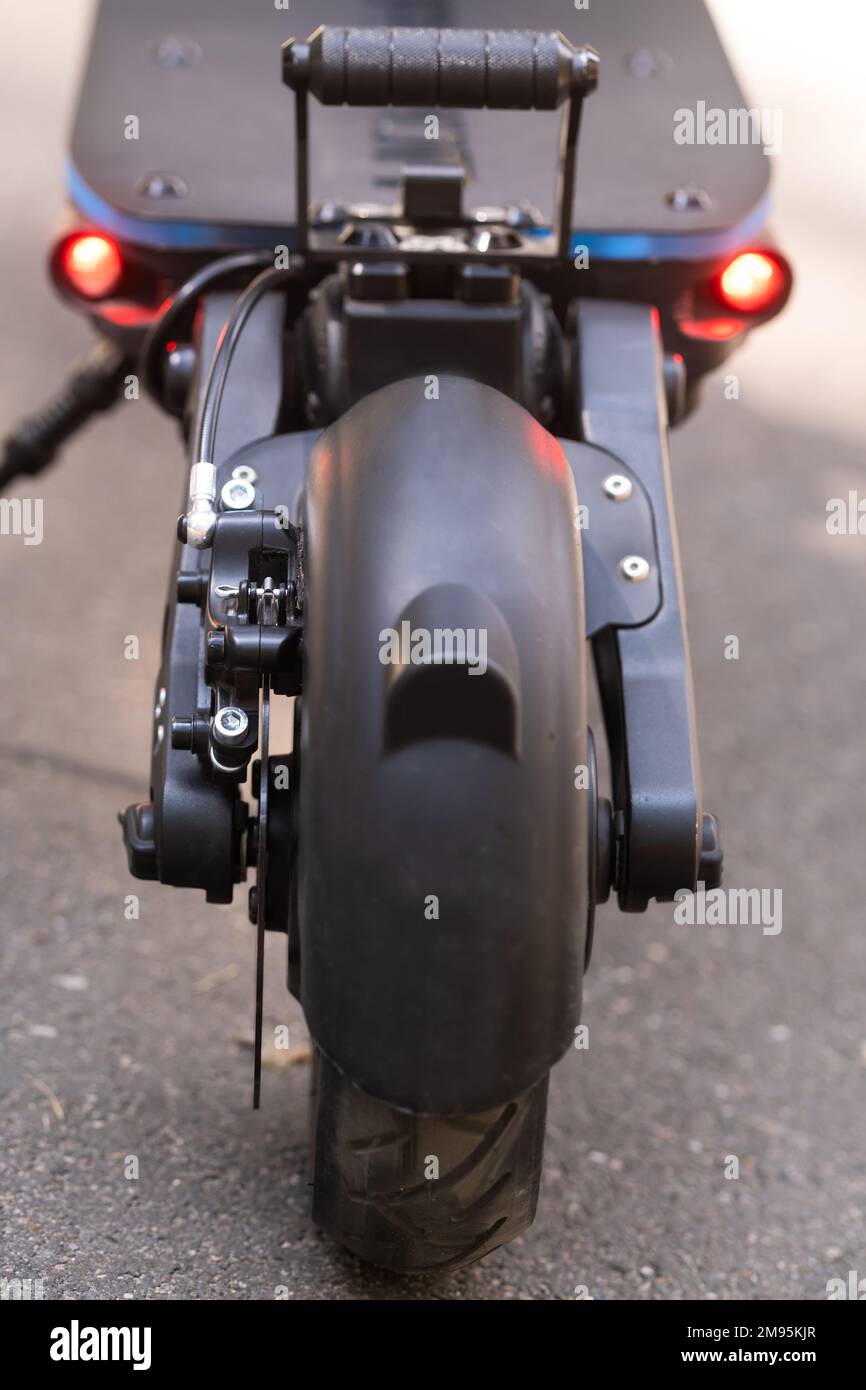 The back of the electric scooter with a foot rest on the asphalt ...