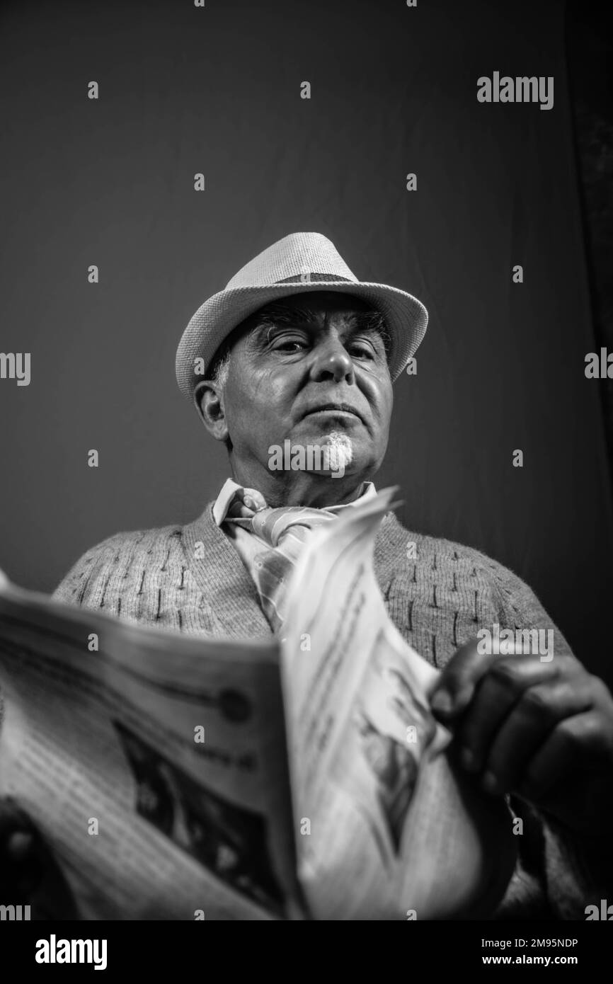 A vertical grayscale closeup of a middle-aged man with a newspaper ...