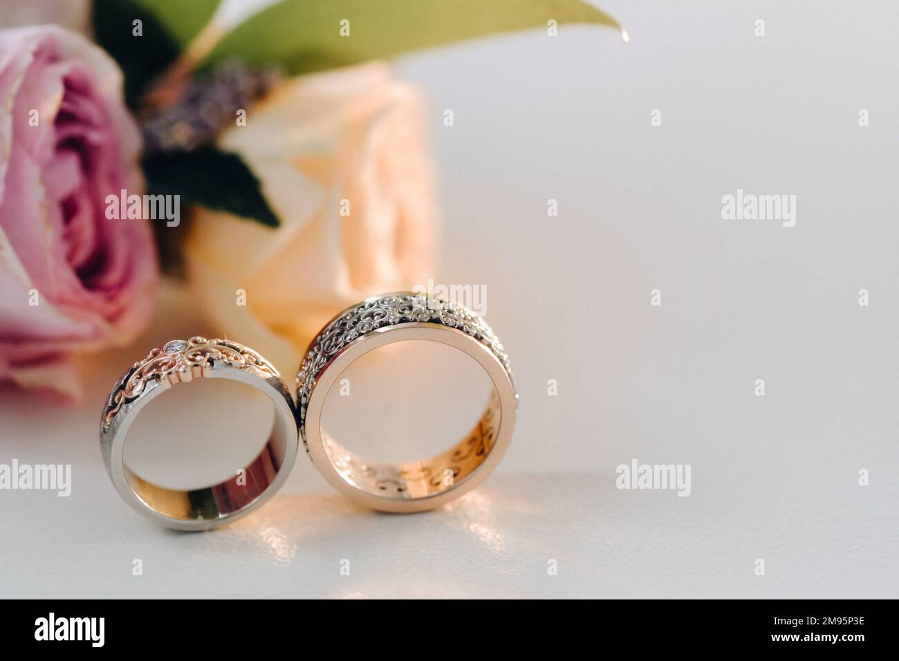 Designer wedding rings lying on the surface with a rose. Two wedding ...