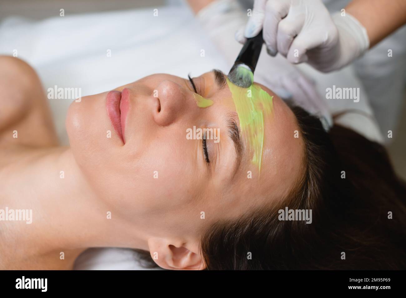 Cosmetologyst apply green face peeling anti-aging mask with brush ...