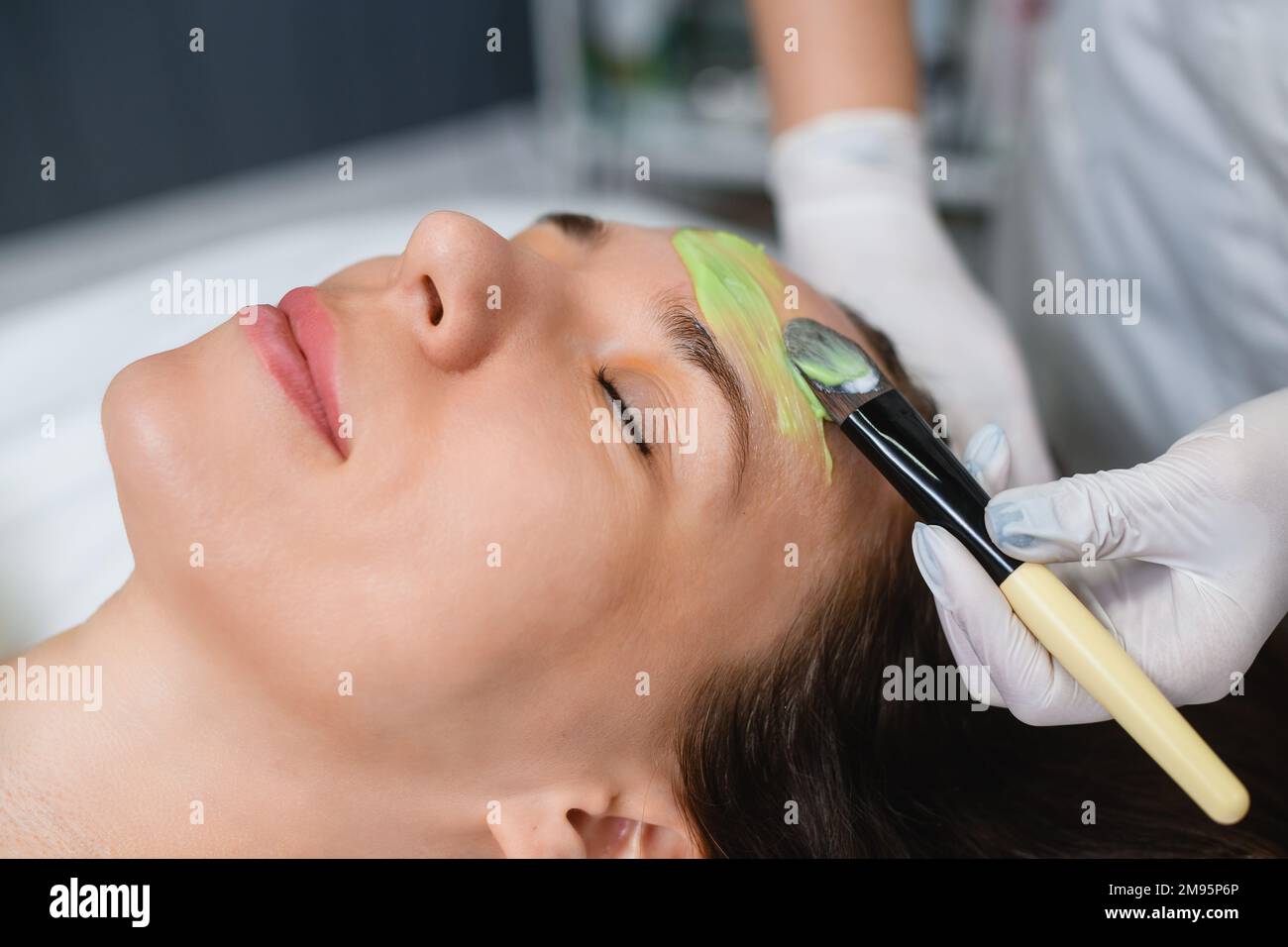 Cosmetologist apply mask on female face and forehead, professional skin ...