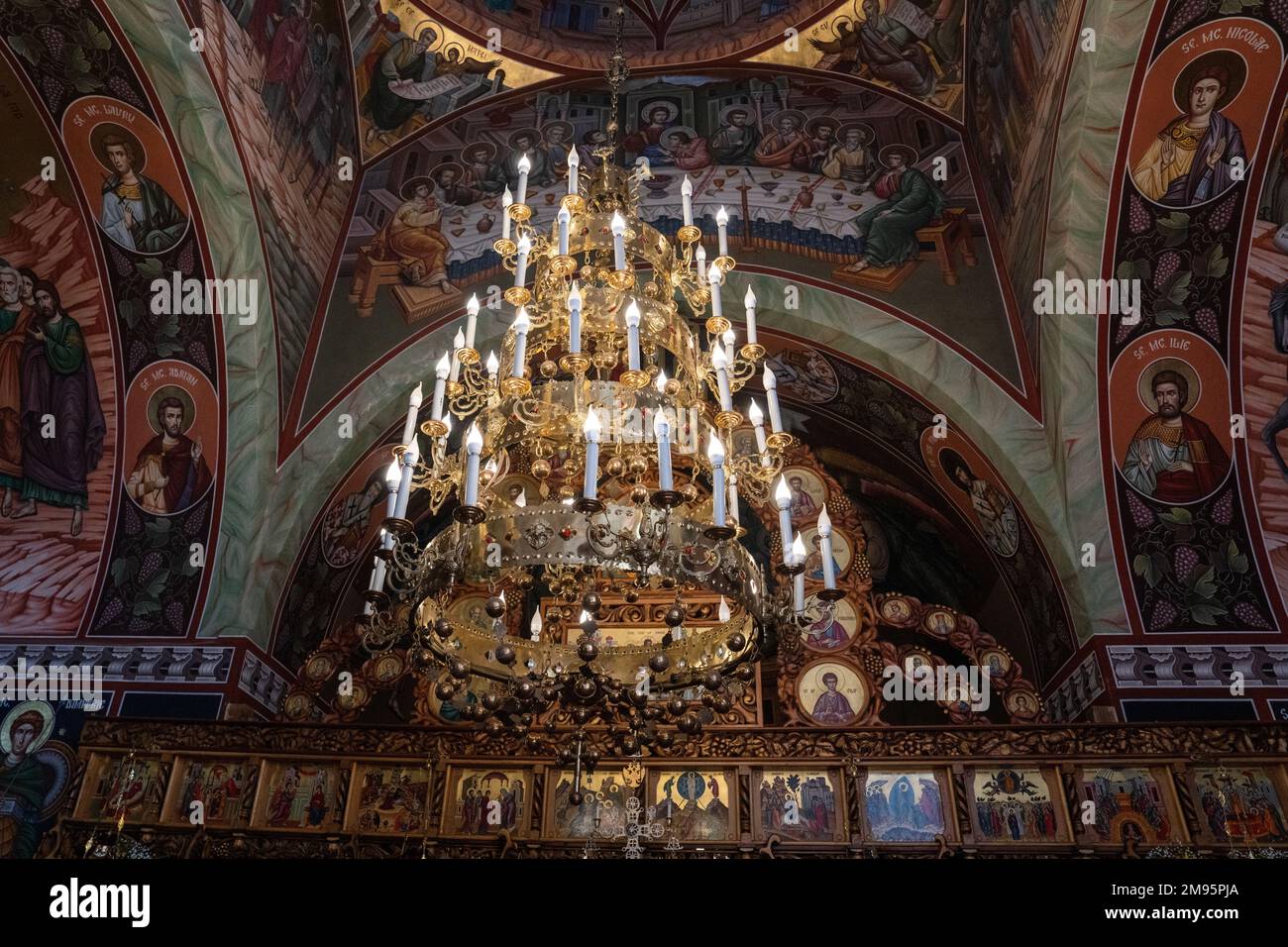 A low-angle shot of a chandelier in a church with paintings on the ...