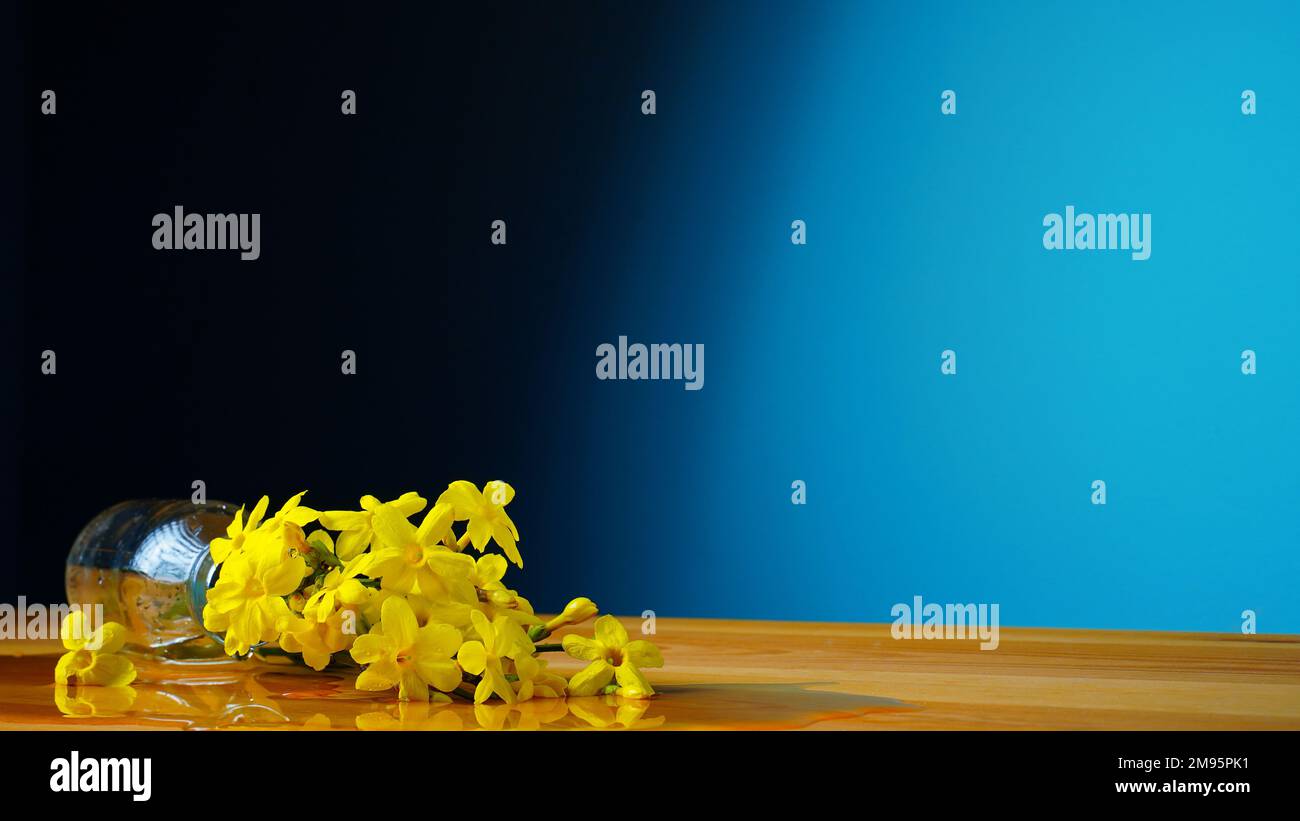 Yellow flowers in fallen bottle with water on blue background ...