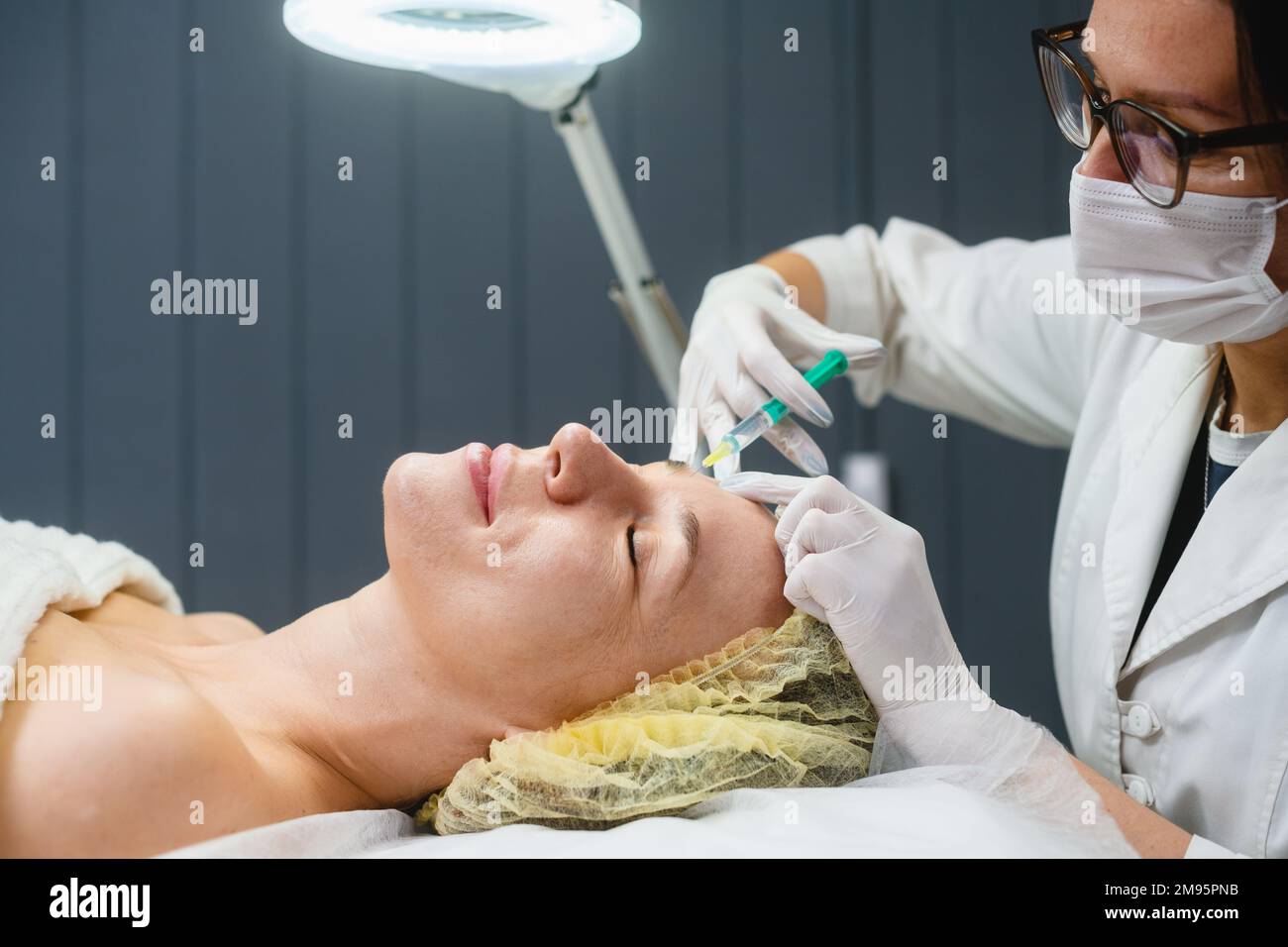 Professional beautician apply skin injections in female forehead, anti ...