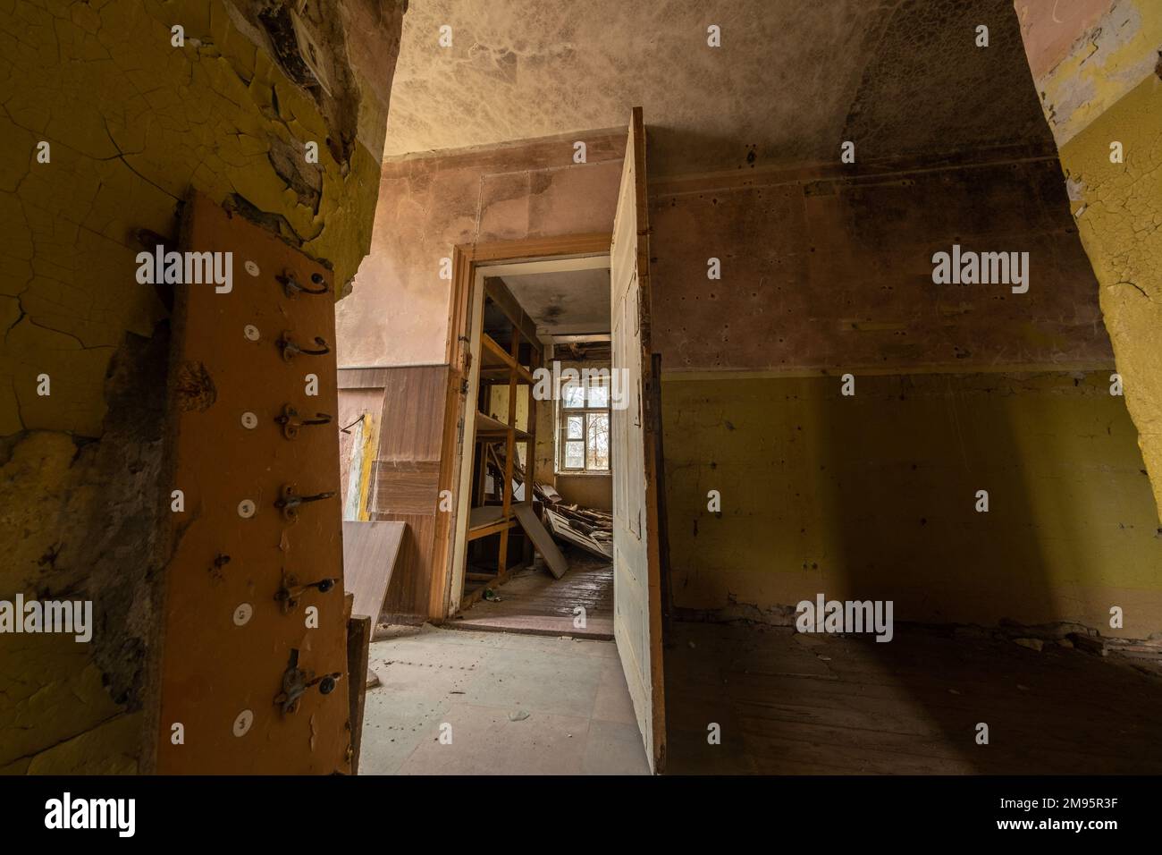 Opened wooden door leading to weathered destroyed room of abandoned ...