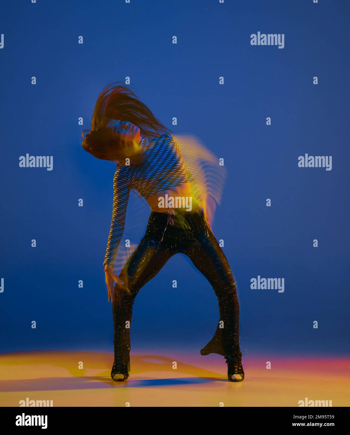 Dynamics. Portrait of young girl dancing heels dance over blue ...