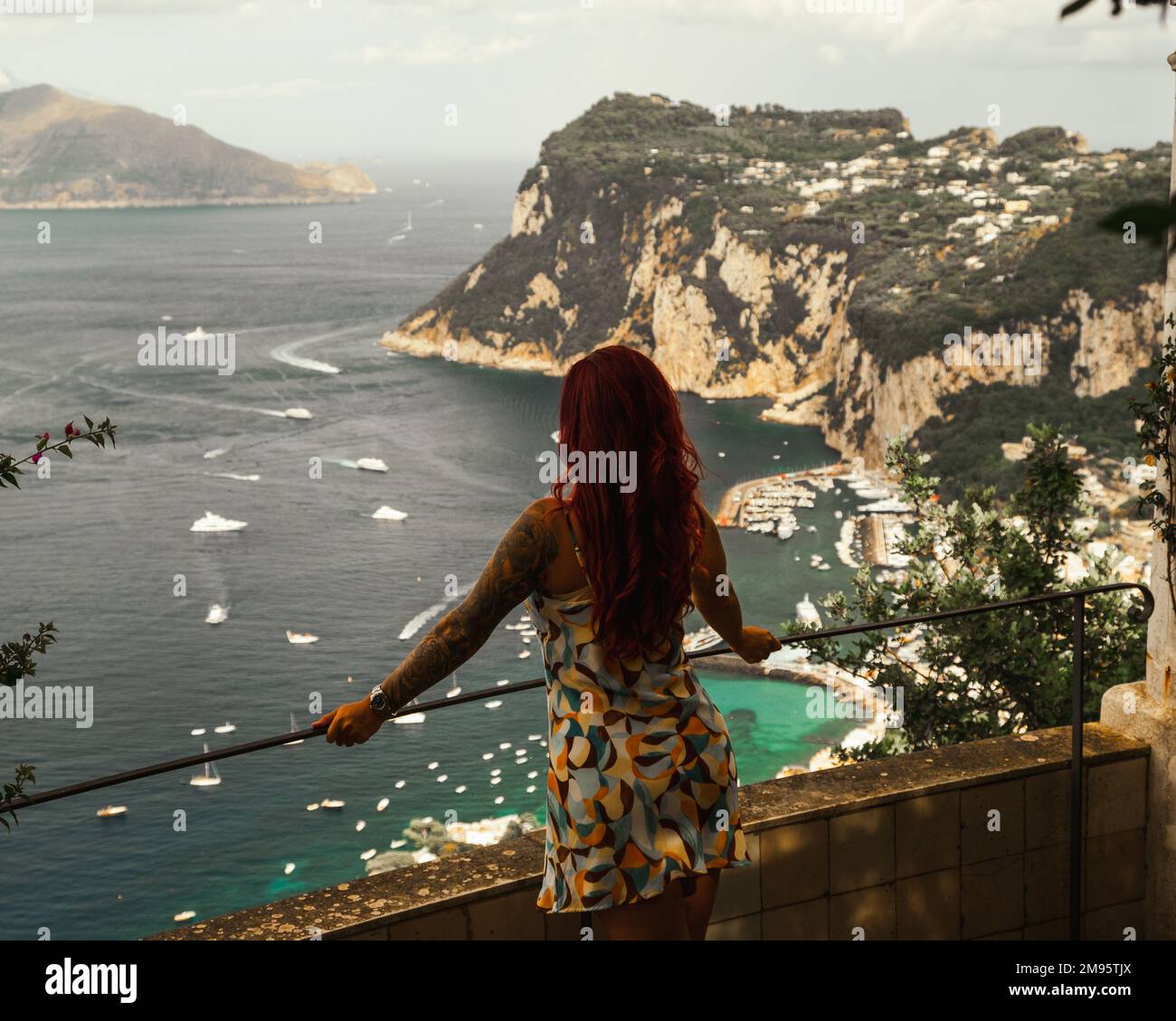 A back view of a woman in a dress overlooking amazing cliffs of Naples ...