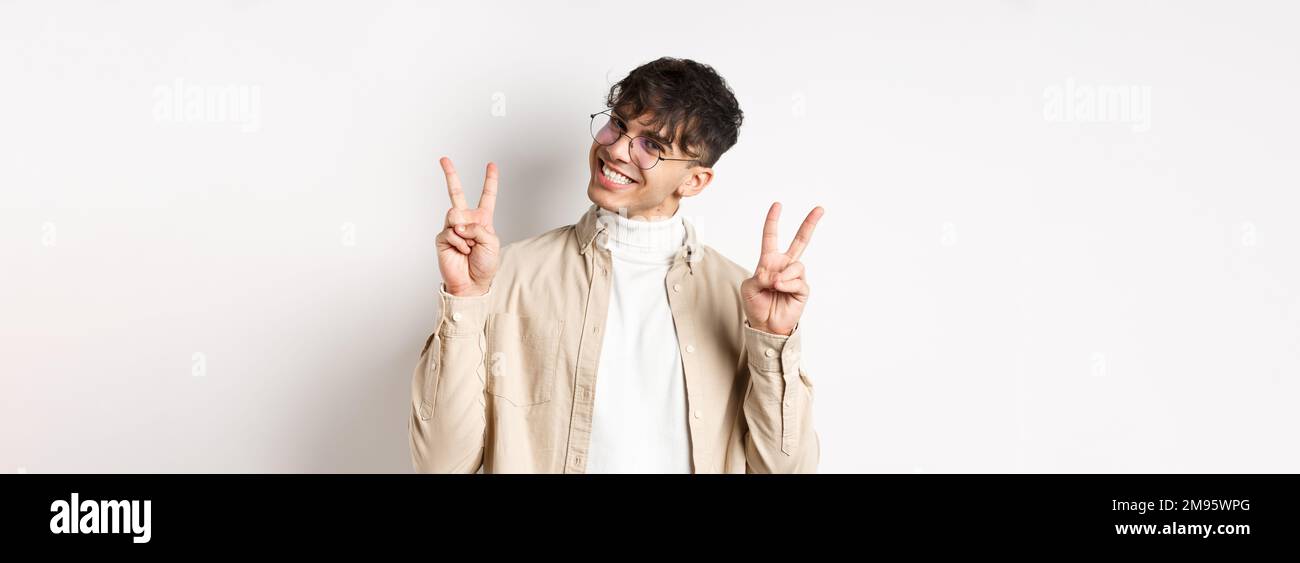 Real people. Handsome hipster guy in glasses showing peace gestures and ...