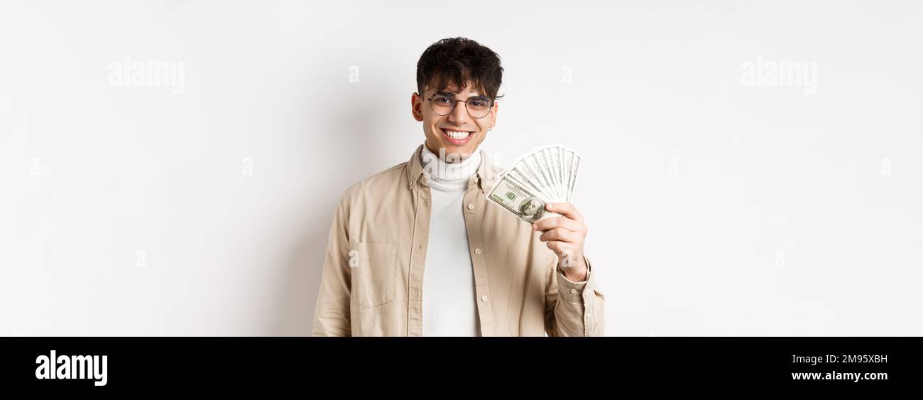 Happy young guy holding dollar bills and smiling, making money and ...