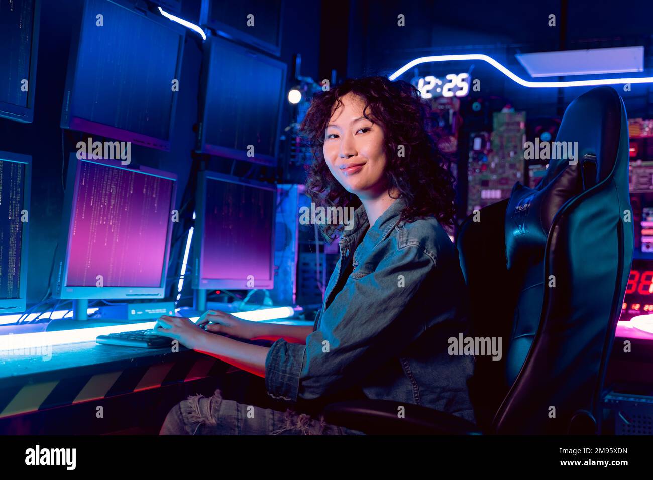 Female Asian hacker smiling in hideout place with dark environment and ...