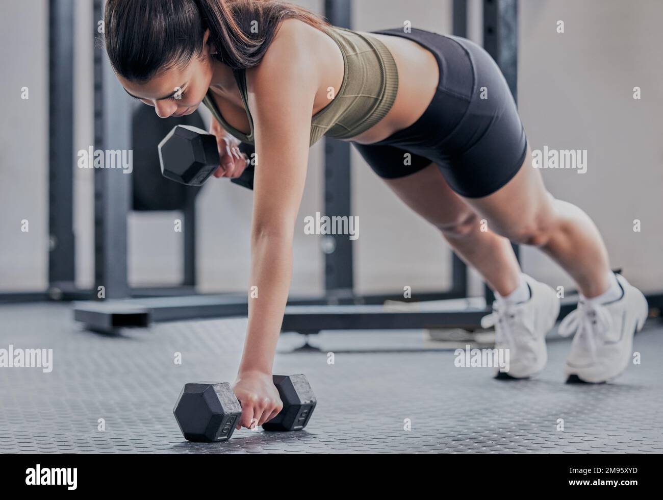On a muscle building mission. a young woman working out with weights in ...