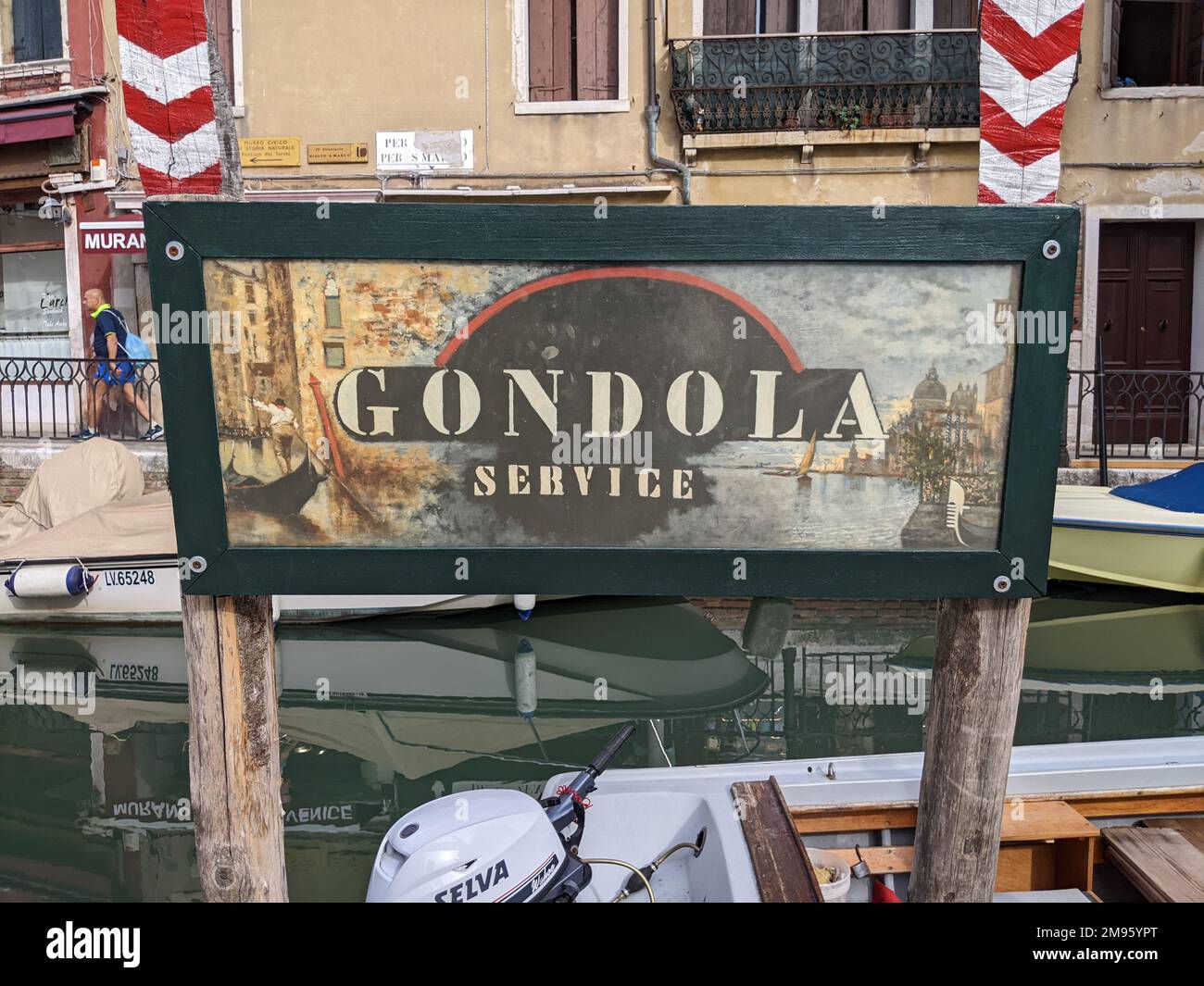 A Gondola Boat service sign with a water channel and buildings in the ...