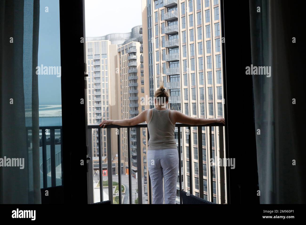 Back view of Young woman standing on balcony Stock Photo - Alamy