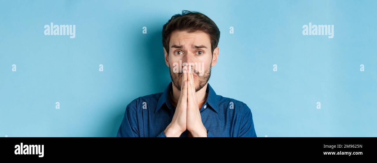 Close up of sad young man pleading, begging for help and say please ...