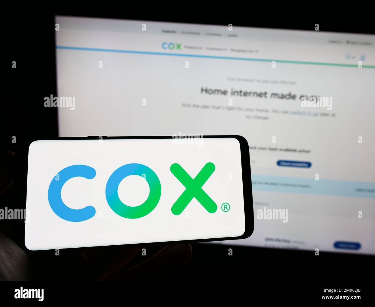 Person holding cellphone with logo of American cable TV company Cox Communications Inc. on ...