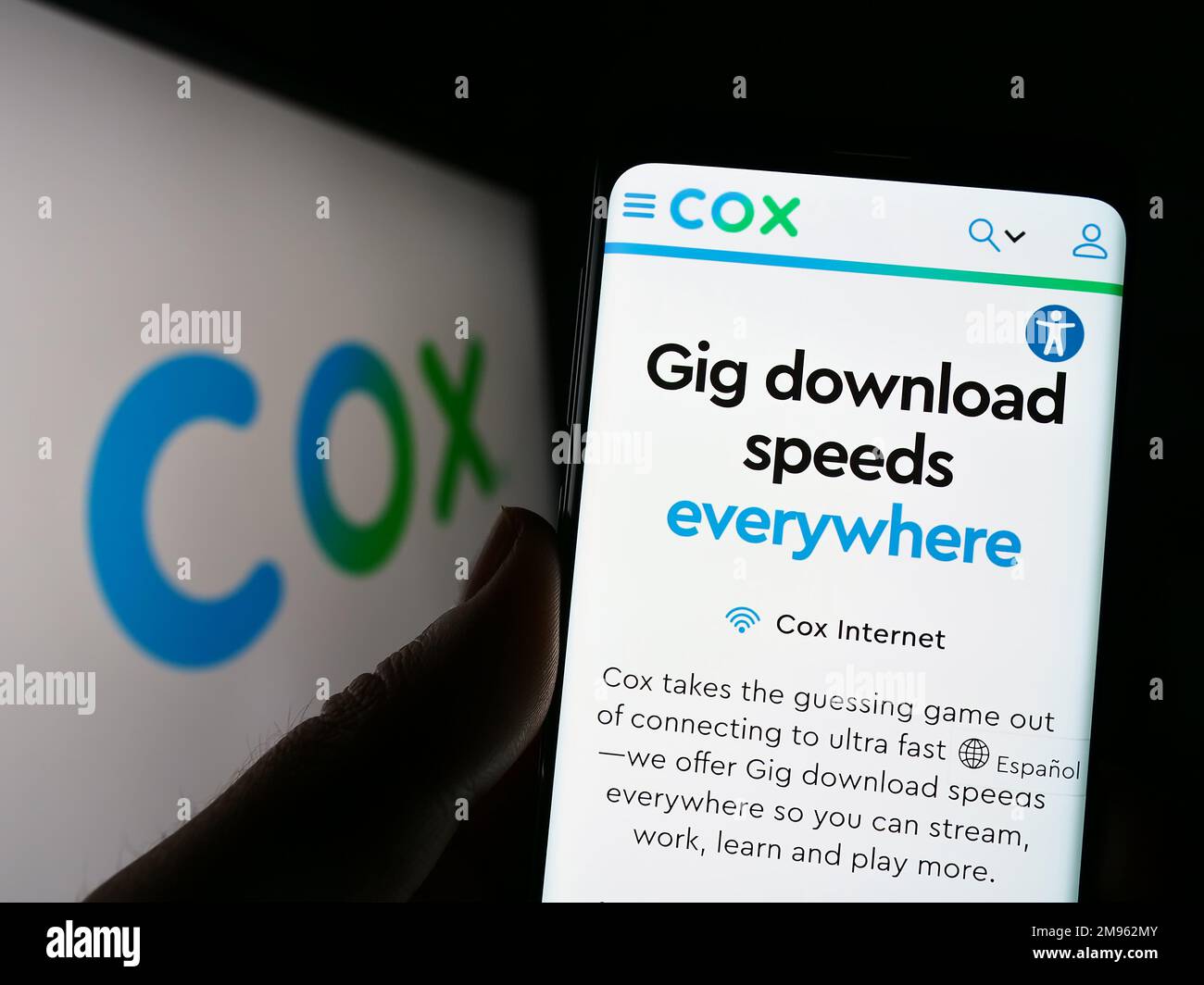 Person holding cellphone with webpage of US cable TV company Cox Communications Inc. on screen ...