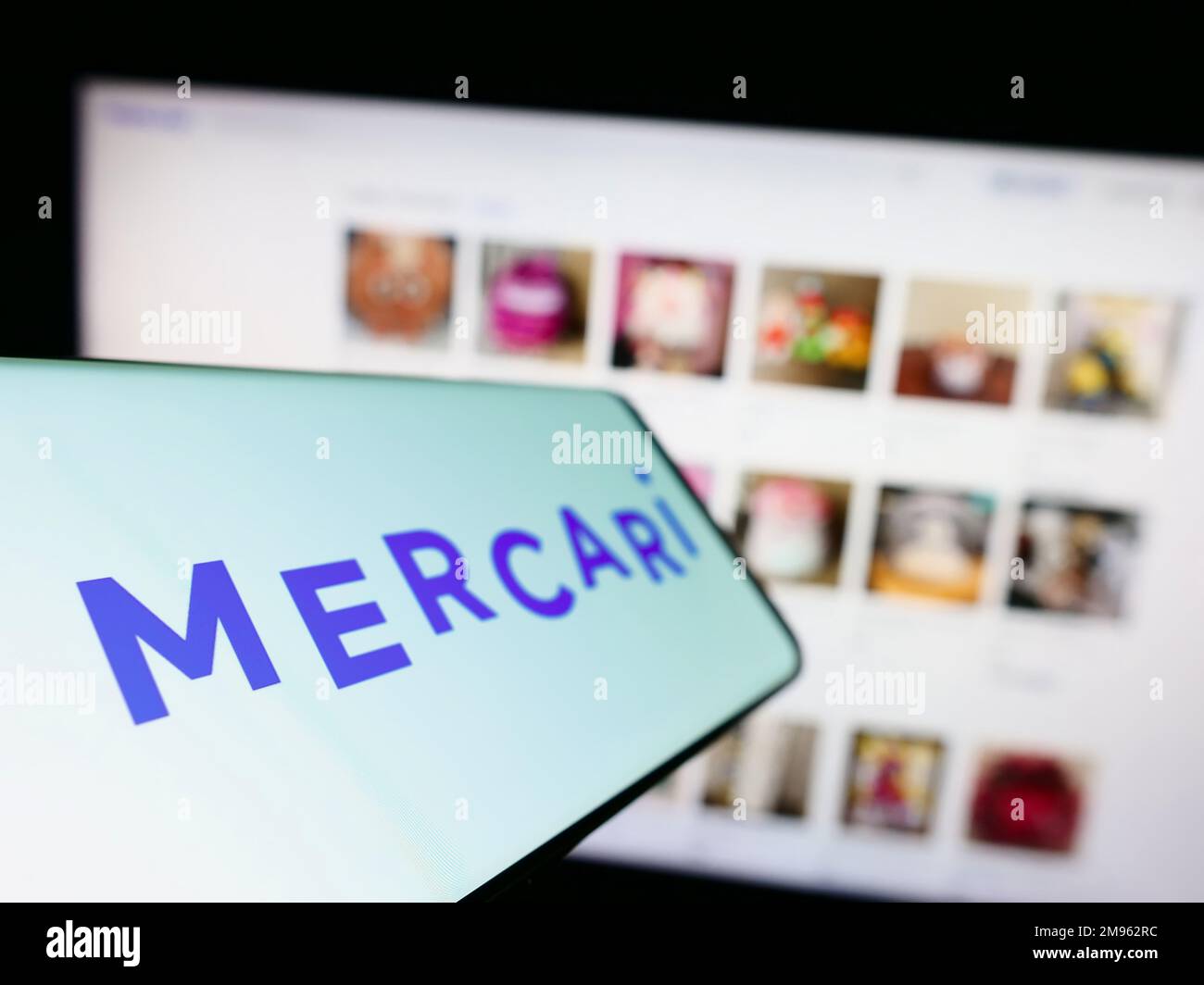 Mobile phone with logo of Japanese e-commerce company Mercari Inc. on screen in front of ...
