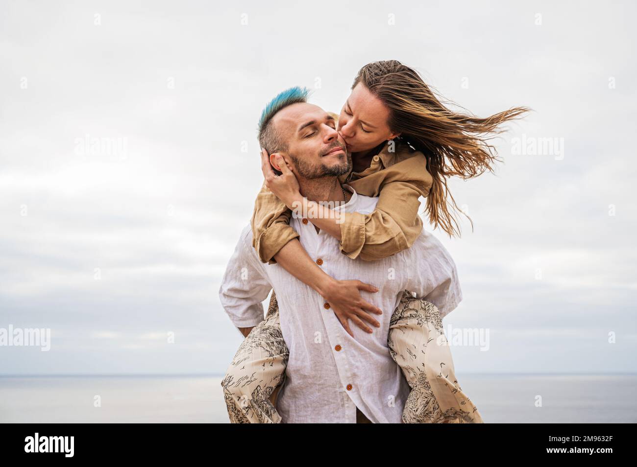 A close-up of a young couple as they kiss while the man carries the ...