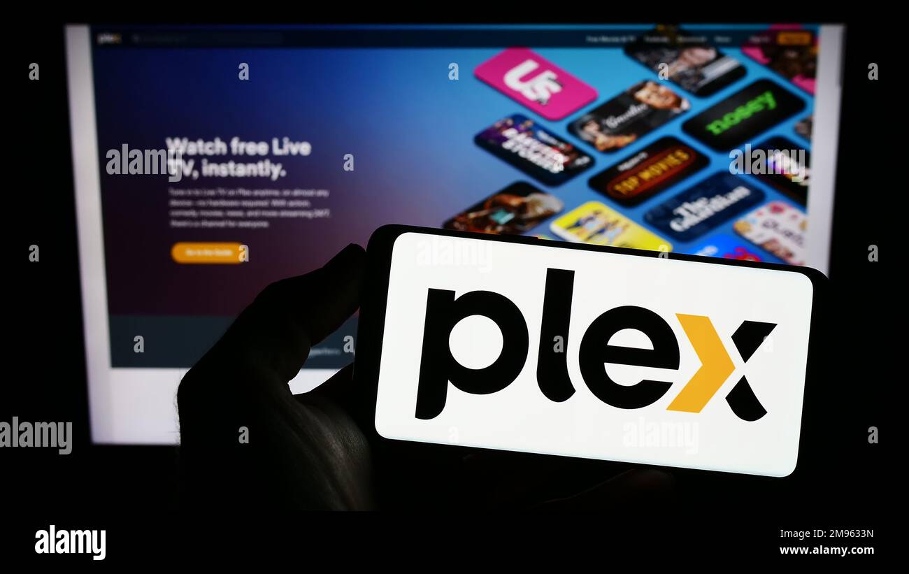 Person holding smartphone with logo of US video streaming company Plex Inc. on screen in front ...