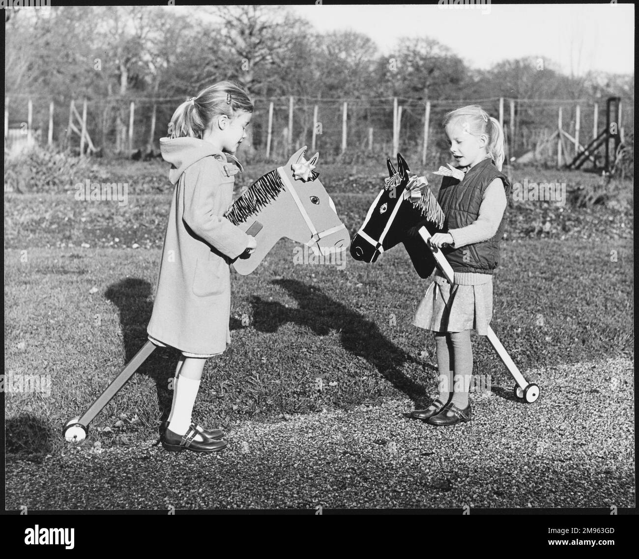 Twin girls with pony tails riding their hobby horses Stock Photo - Alamy