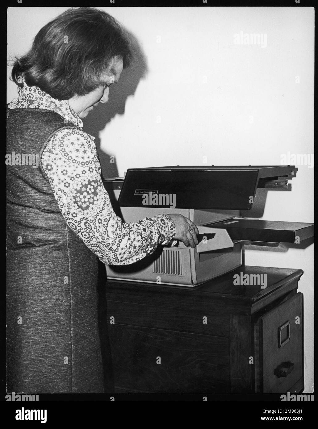 A woman in a floral shirt and with a "page boy" hairstyle, using an ...