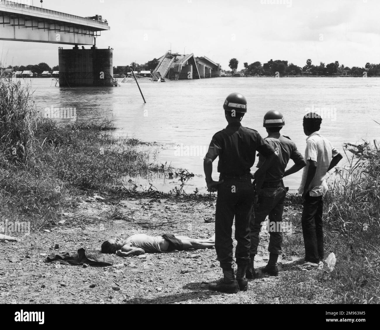 Two soldiers and a civilian stand over the body of a victim of the Viet ...