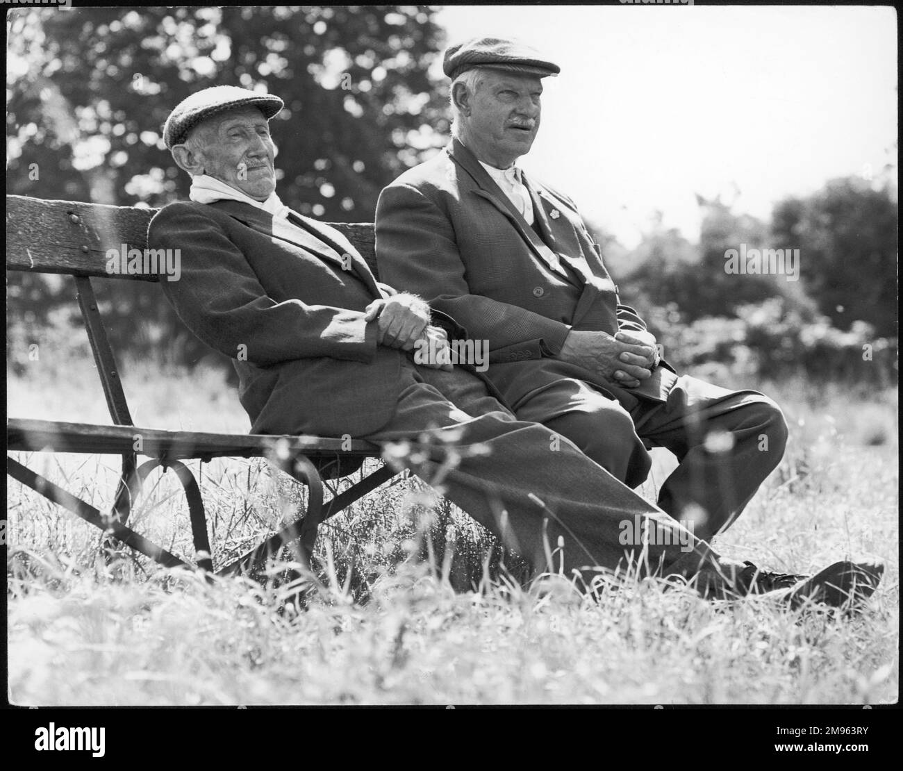 Two elderly men in cloth caps take a breather on a park bench Stock ...