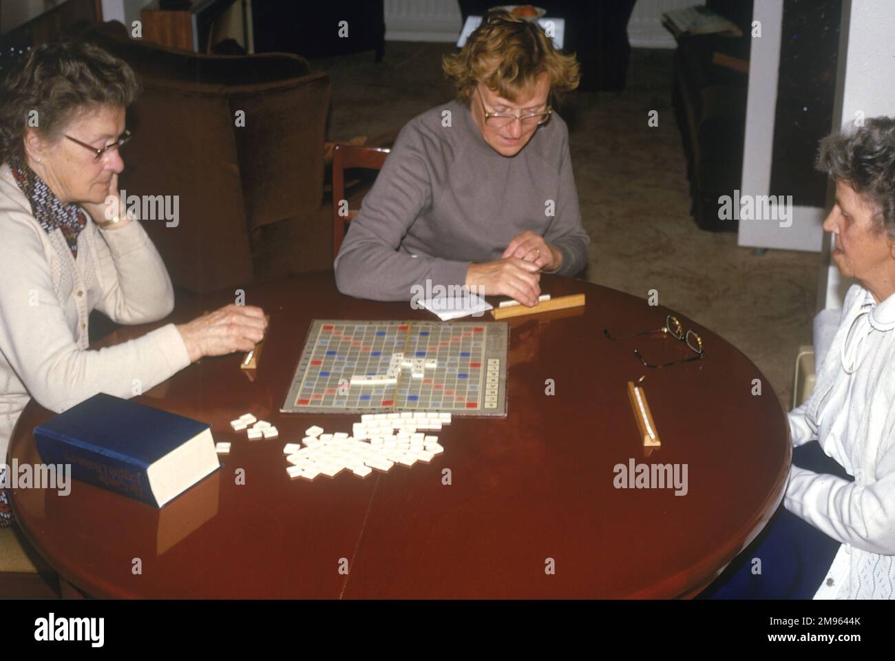 Three women playing the word conundrum game 'Scrabble' Stock Photo - Alamy