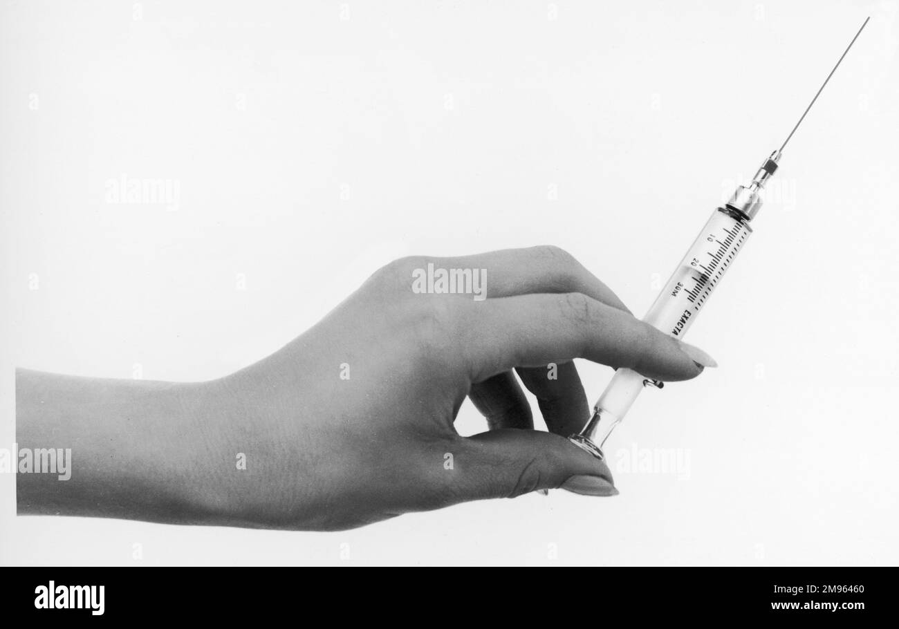 A nurse holds up a syringe, ready to perform an injection on her ...