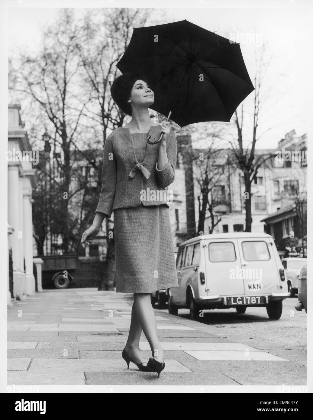 A woman walks down an apparently dry street with her umbrella up Stock ...