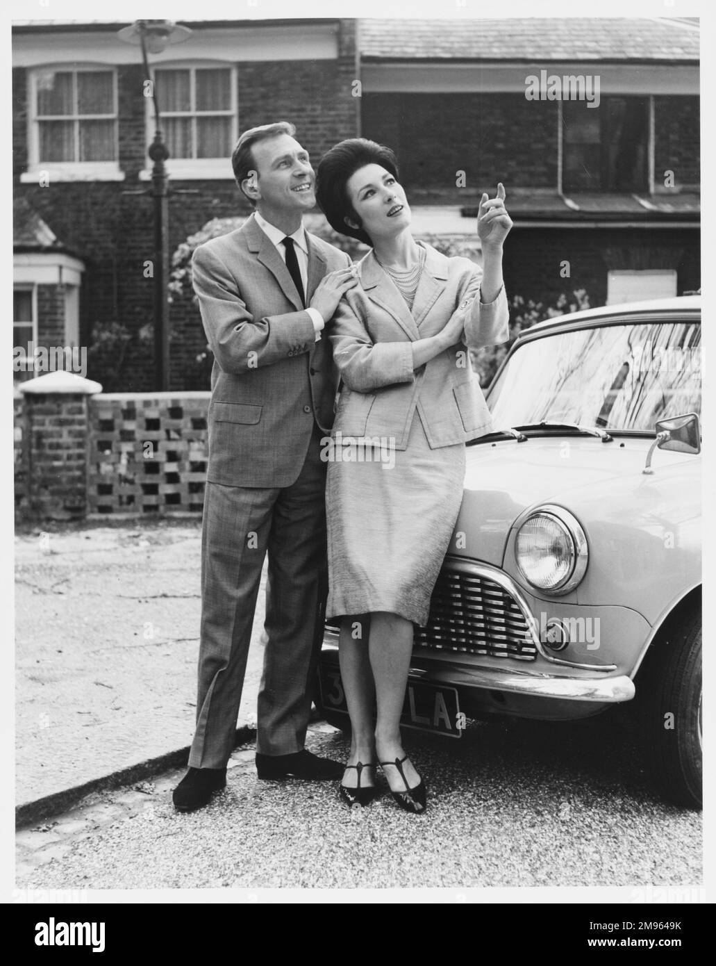 A couple have a look at the front of a house they are interested in ...